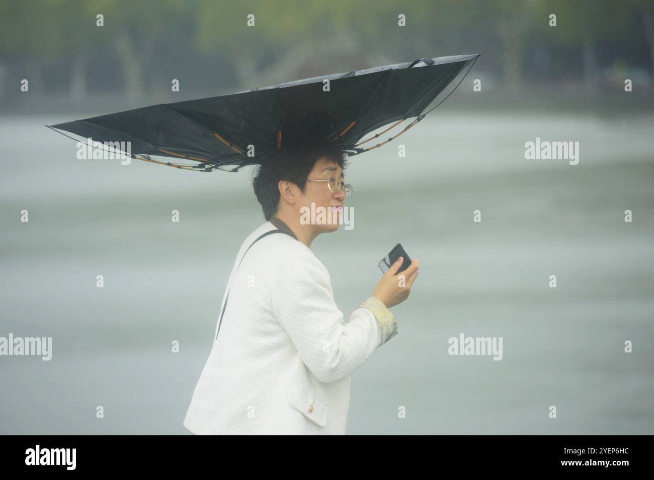 HANGZHOU, CHINA - NOVEMBER 1, 2024 - A tourist braves strong winds and ...