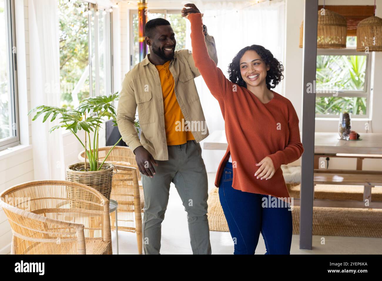 multiracial couple dancing joyfully at home, celebrating Thanksgiving ...