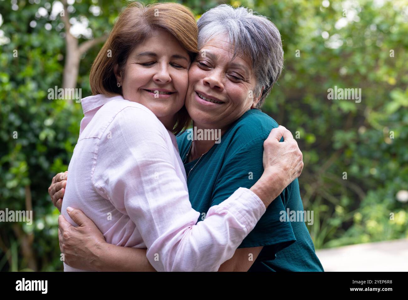 Senior female friends embracing warmly outdoors, sharing joyful moments ...
