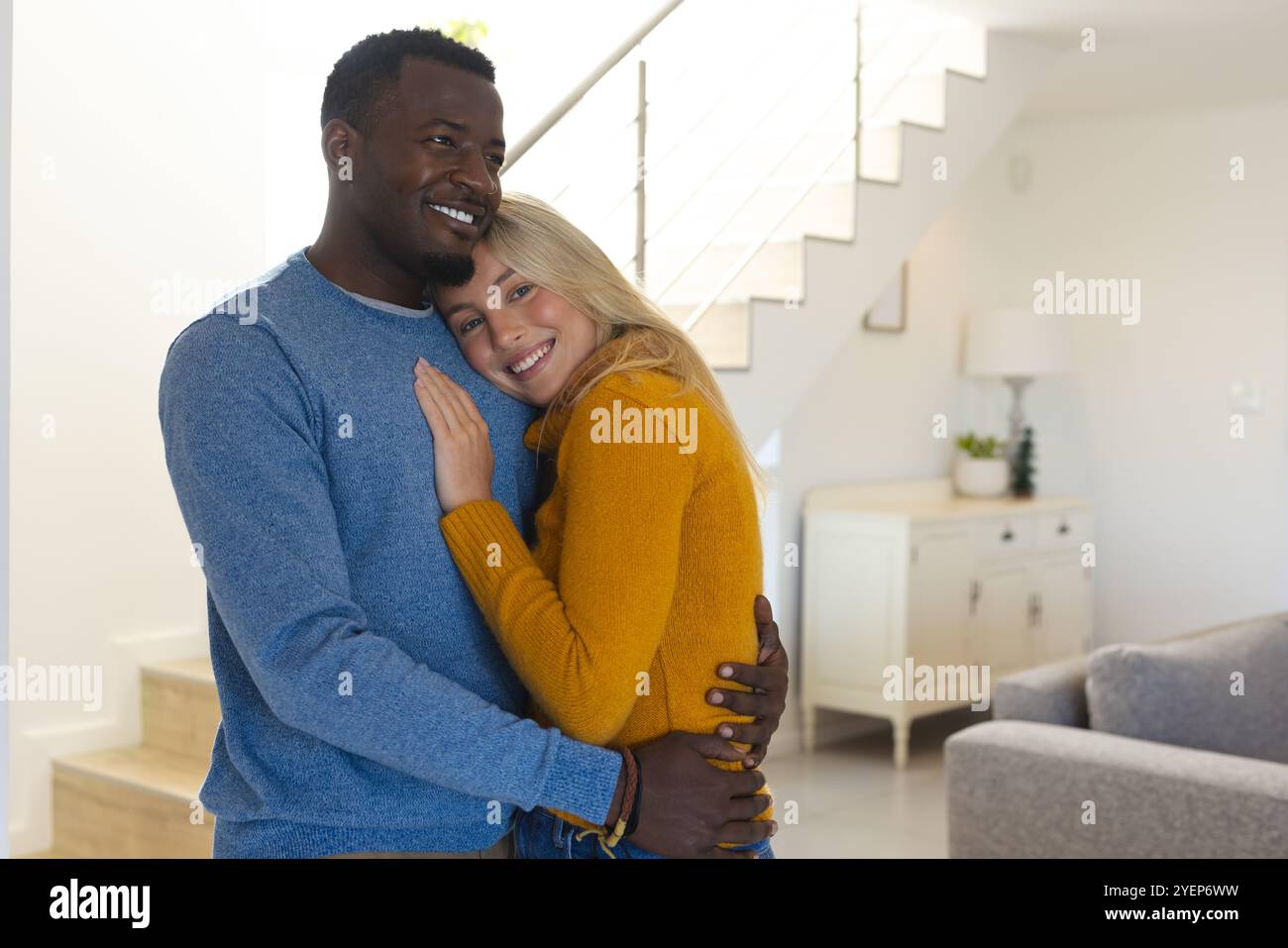 Happy multiracial couple embracing at home, enjoying cozy holiday ...