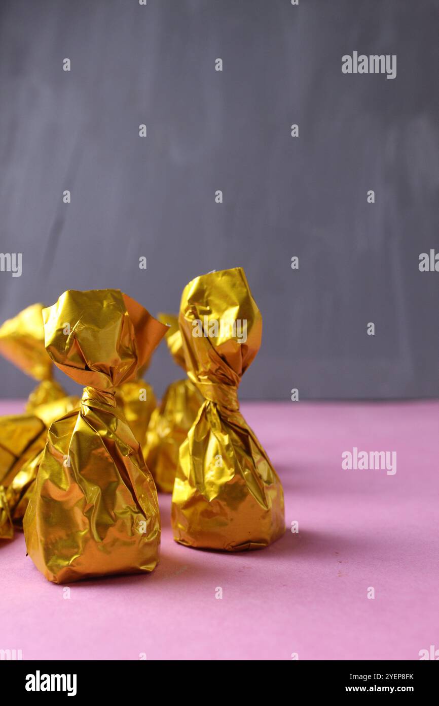 Cut chocolate truffle in a yellow wrapper on a gray background with ...