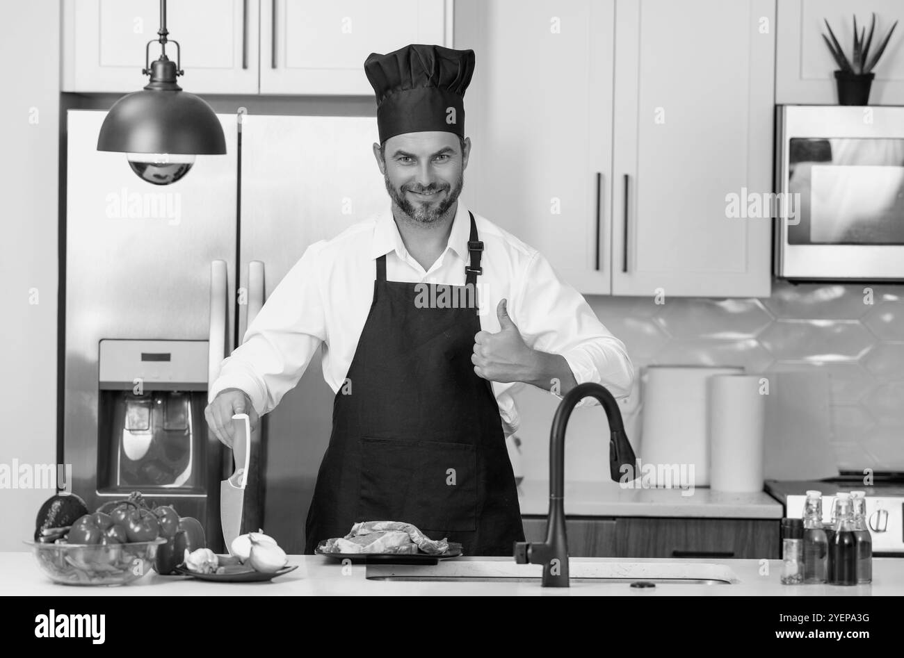 Man in apron and chef hat cooking food in kitchen. Handsome man cooking ...