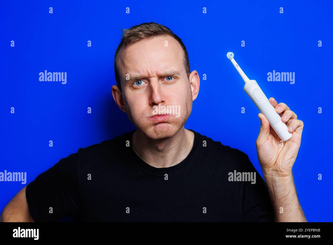 Portrait of a young handsome man brushing his teeth with an ultrasonic modern toothbrush. Oral ...