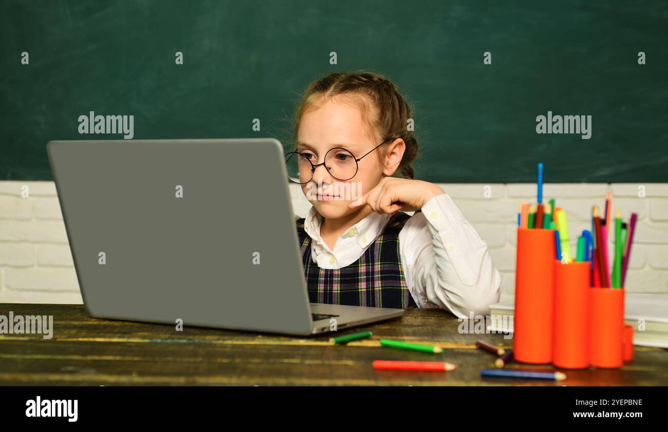 Pupil working on laptop computer over blackboard background. School ...
