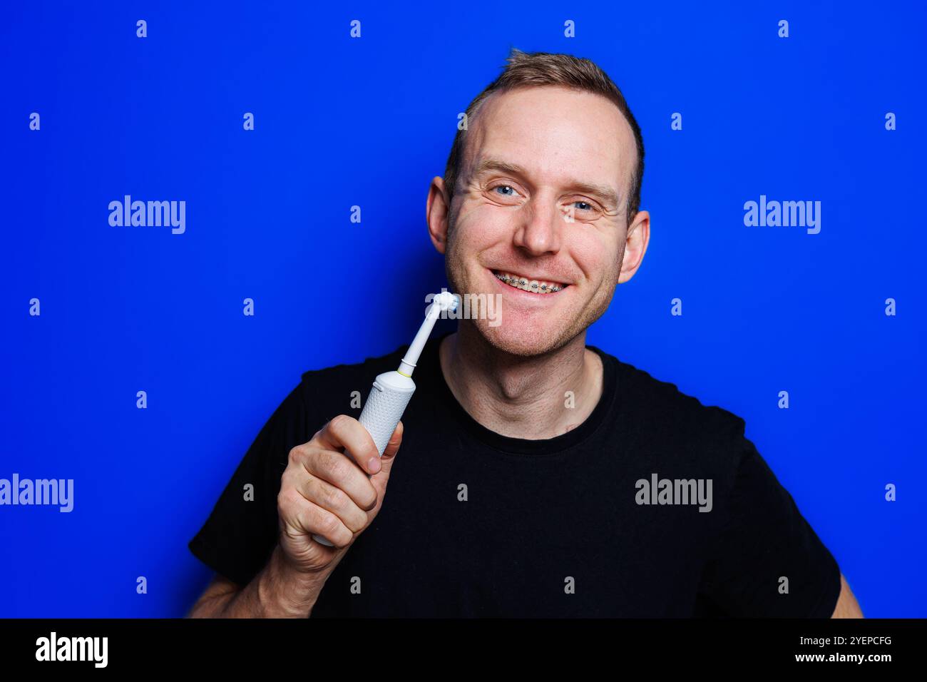 Portrait of a young handsome man brushing his teeth with an ultrasonic ...