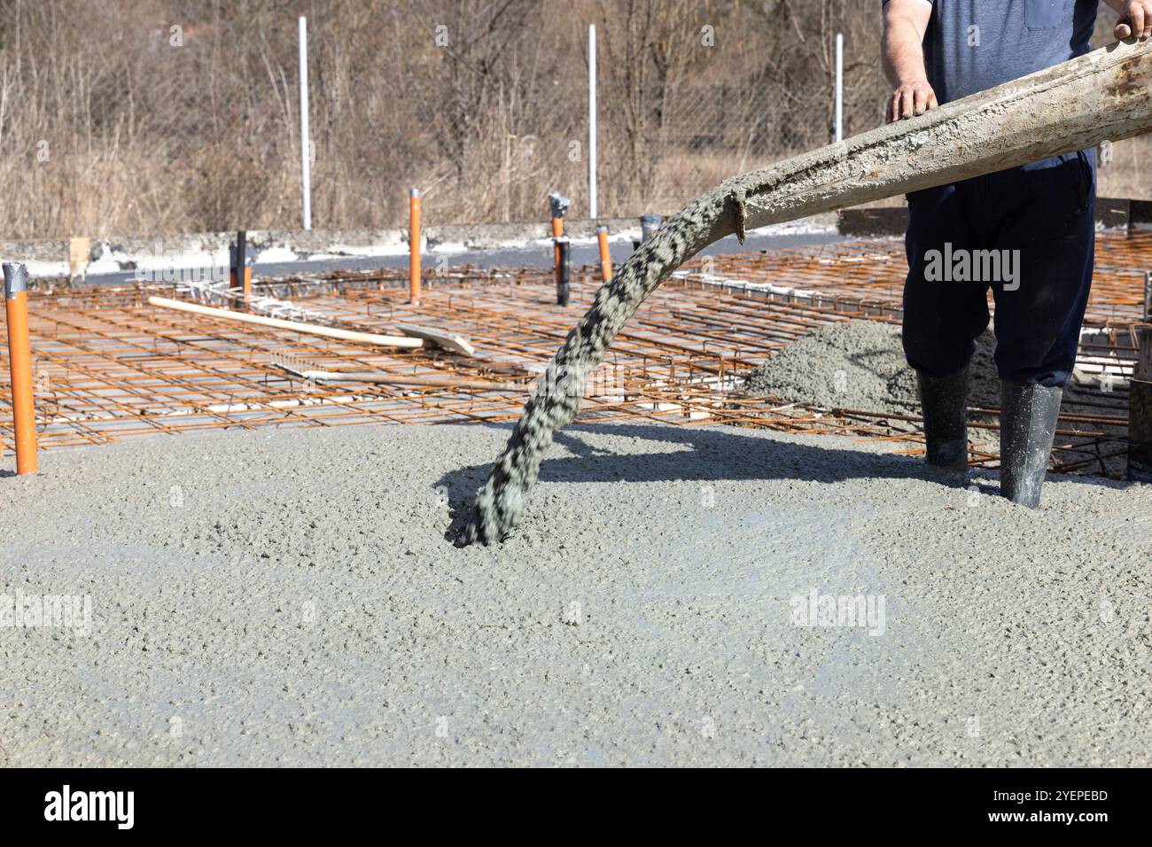 Worker builder pouring concrete from a concrete mixer on a construction ...