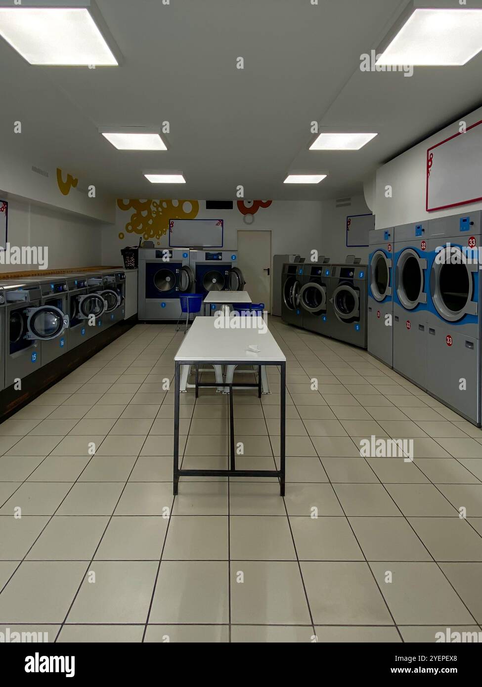 Clean laundromat interior with washers and dryers lined up. High ...