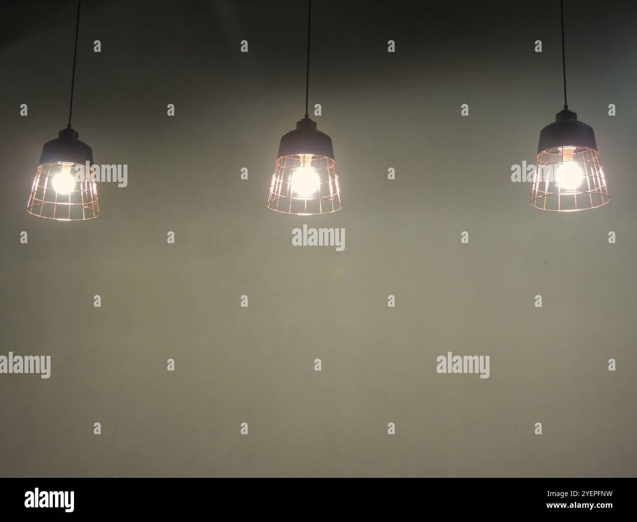 three glowing lamps on long cords against the wall as an element of ...