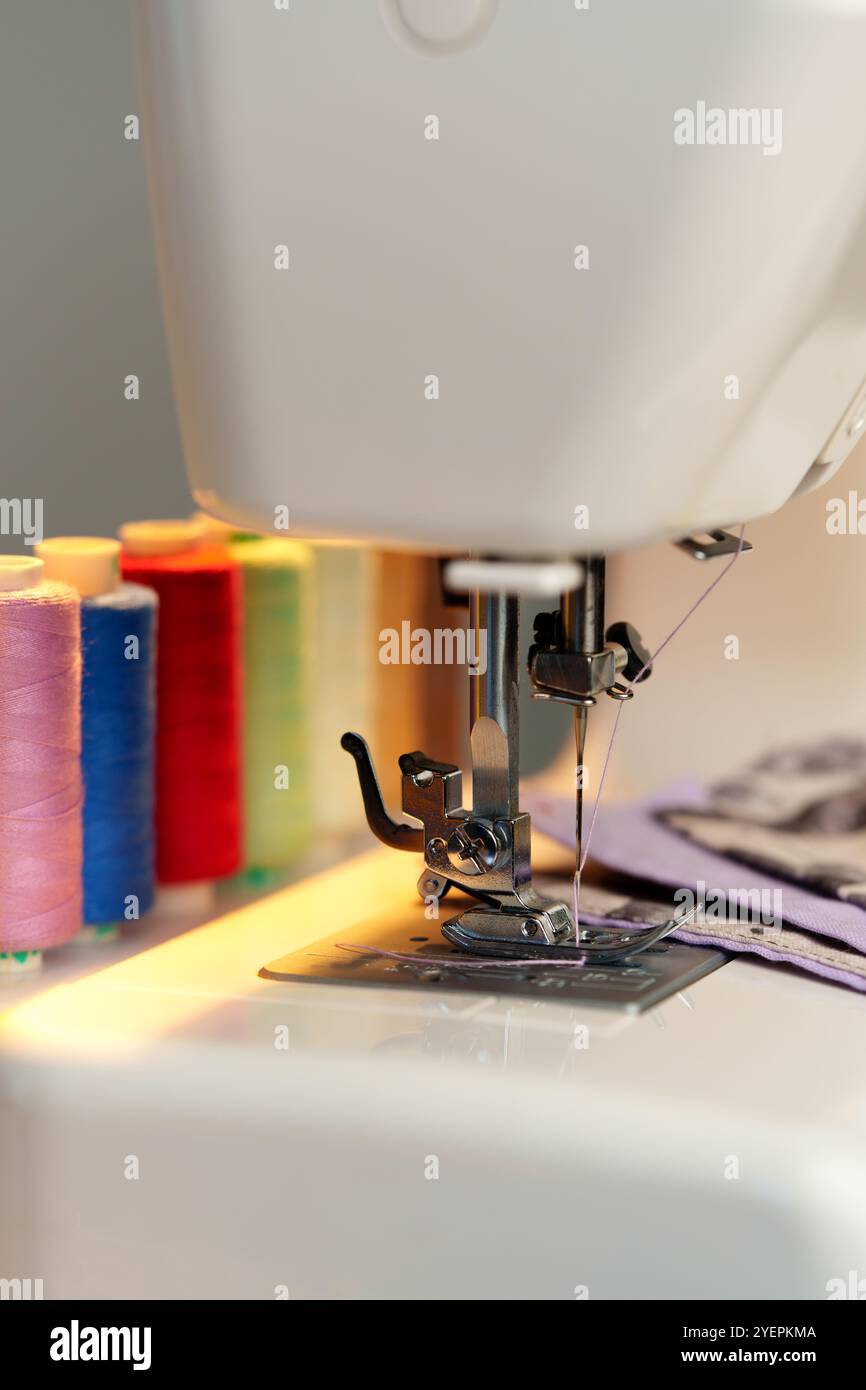 Colorful threads lined up beside a sewing machine ready for creative ...