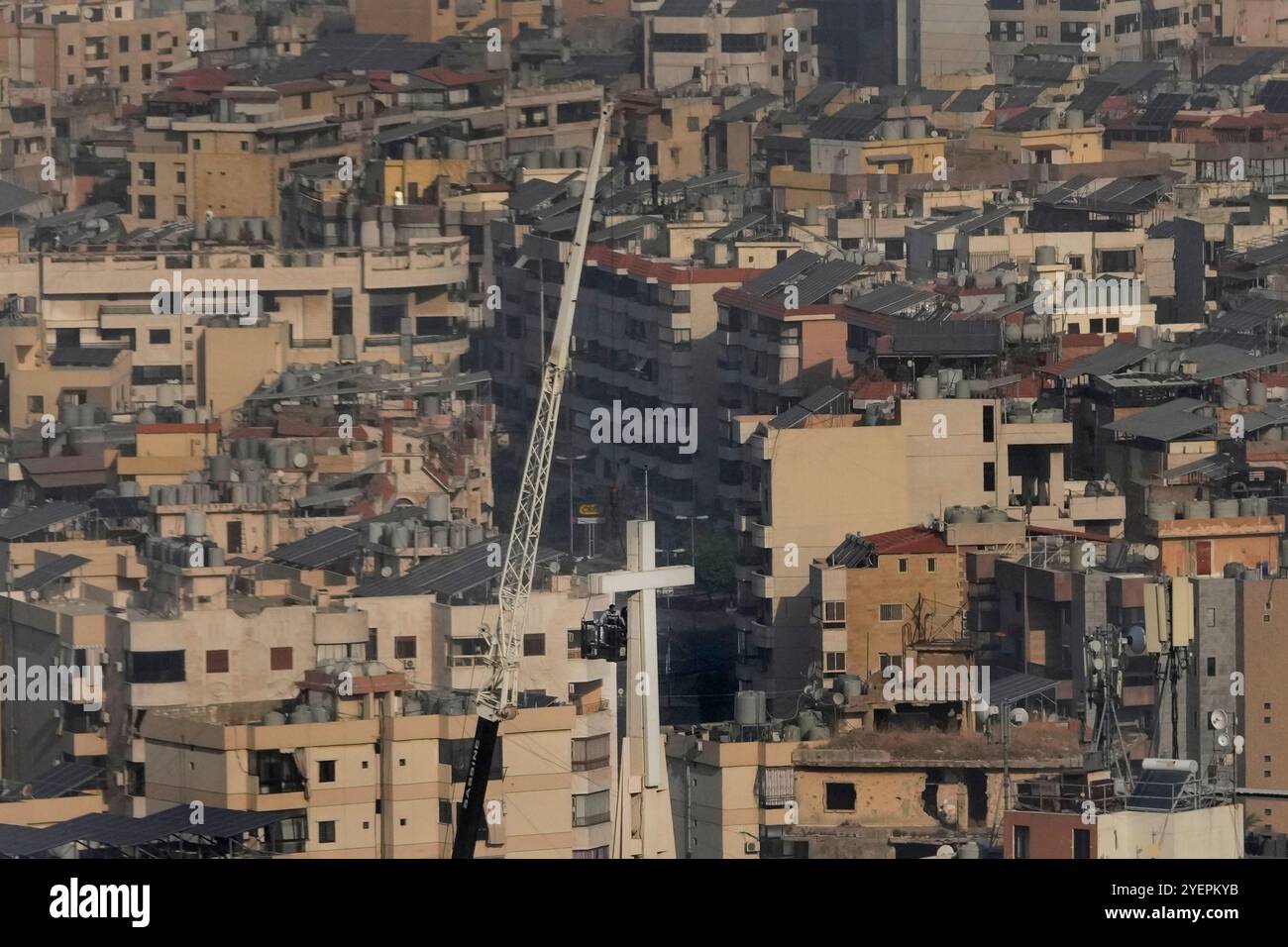 Workers in a crane basket, fix the giant cross of Our Lady of Hadath ...