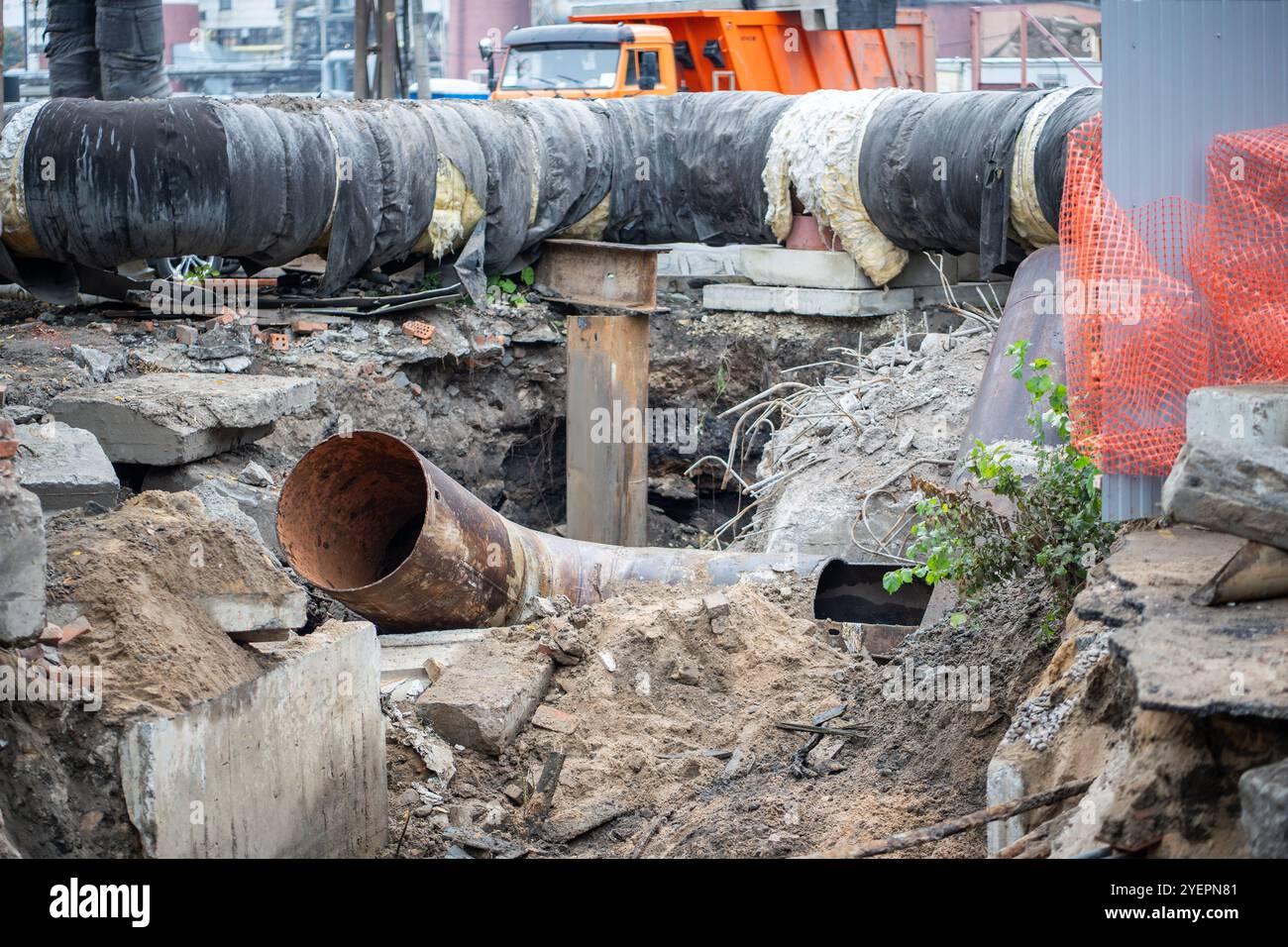 Scattered fragments of water, gas pipes in excavated trench. Worn pipe ...