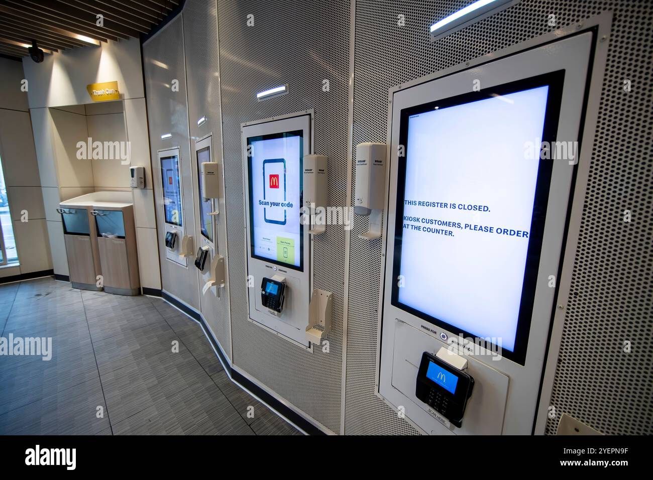 The image displays a series of self-service kiosks inside a modern fast ...