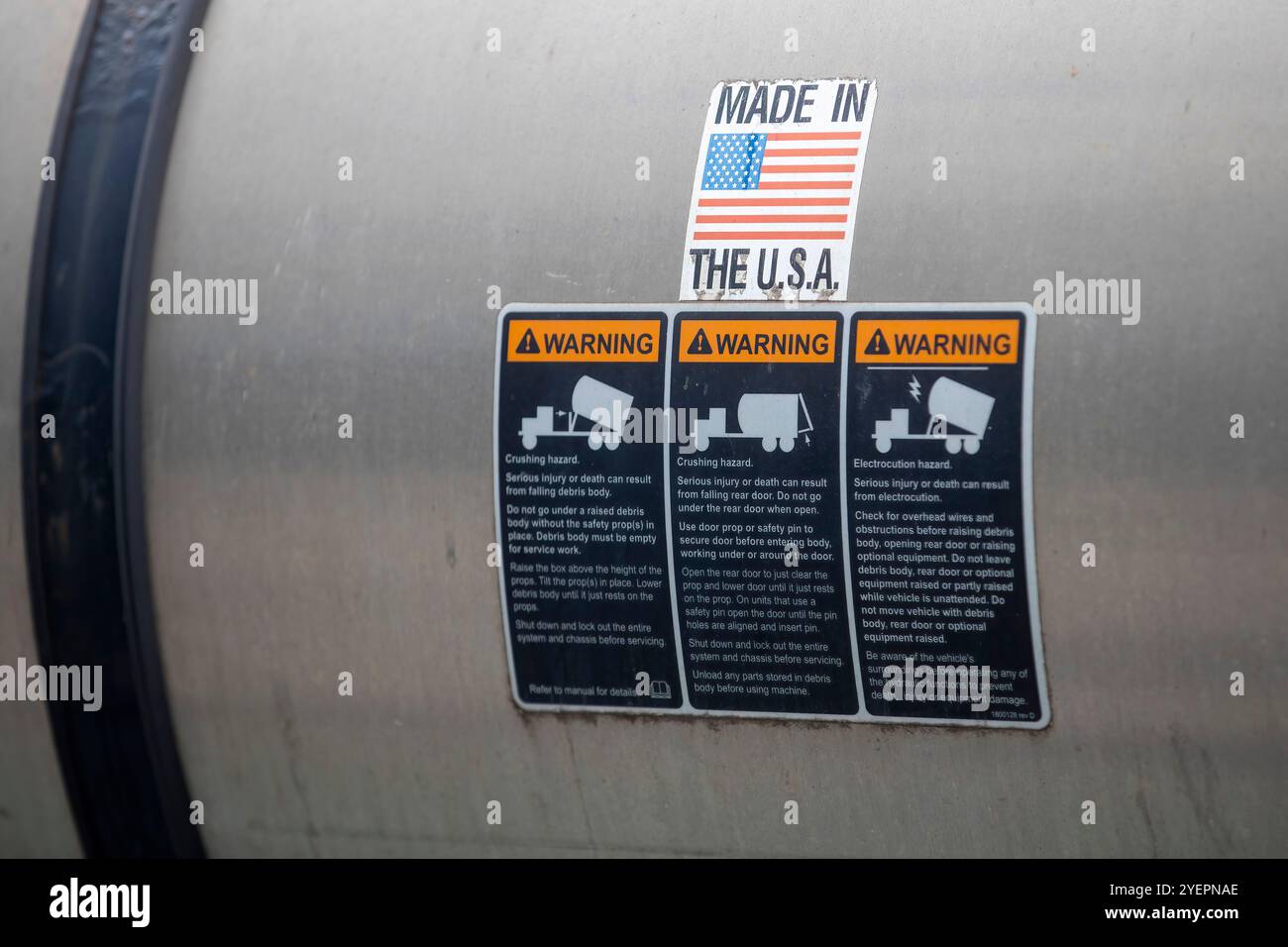 The photograph shows a metallic surface with several warning labels ...