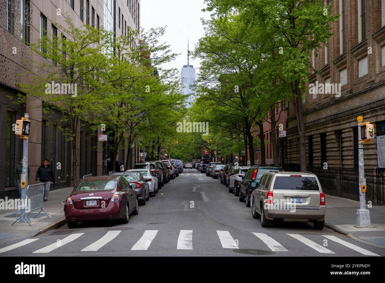This image captures a street view lined with parked cars on both sides ...