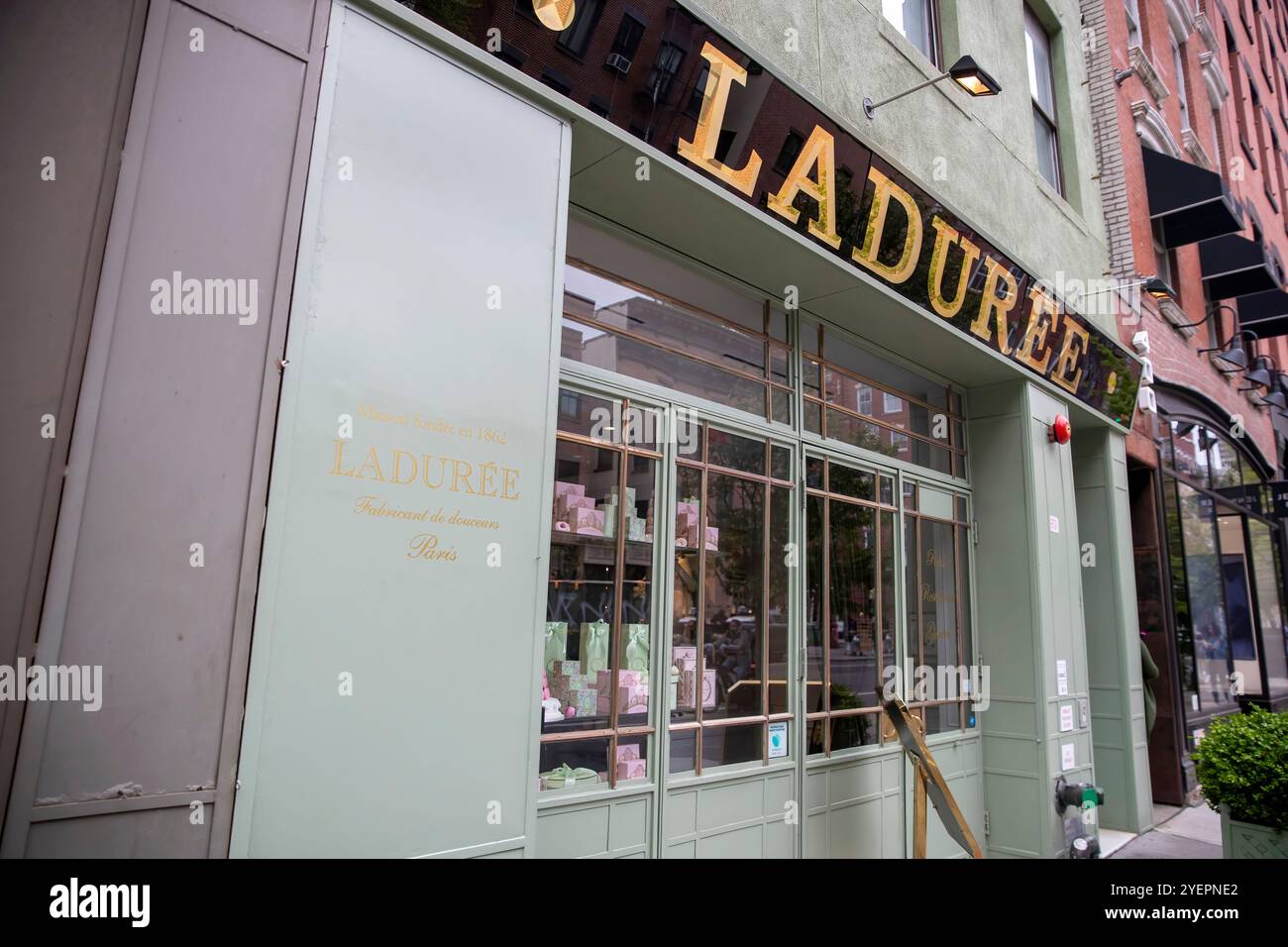 This photograph shows the exterior of a Ladurée storefront, featuring ...