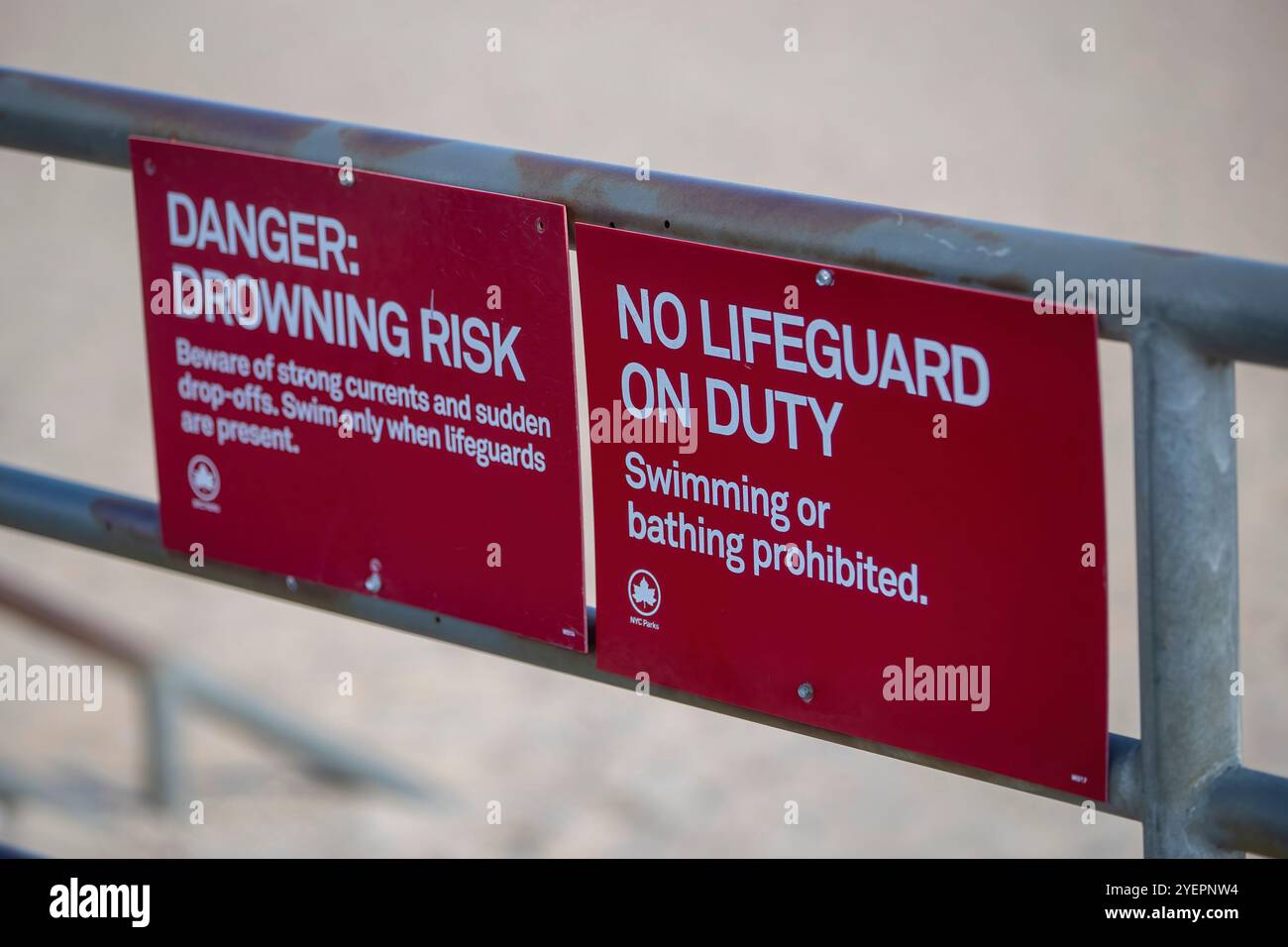 This image displays a red warning sign near the beach, emphasizing ...