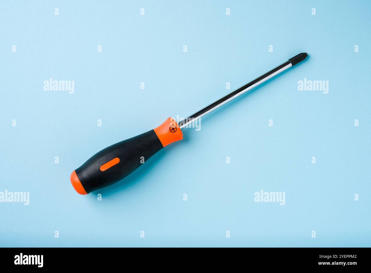 Orange and black rubber-handled Phillips screwdriver on blue background ...