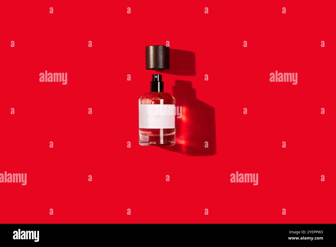 A sleek perfume bottle with a black cap on a red background. Perfect ...