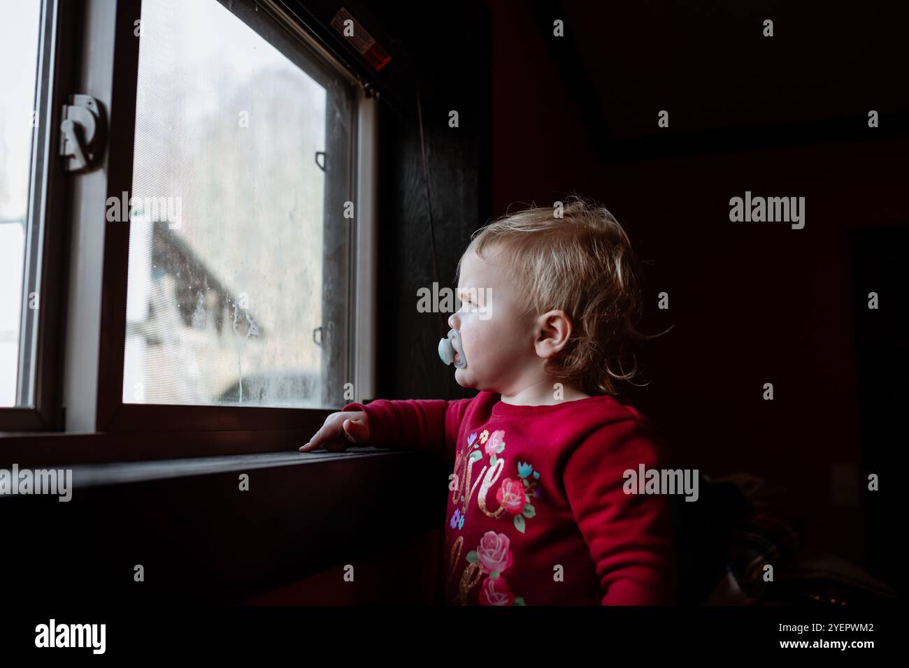 Toddler with pacifier in home looking out window Stock Photo - Alamy