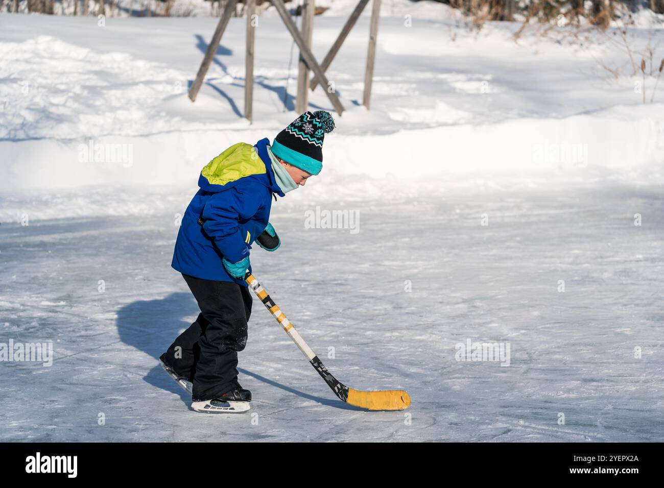 Young child ice skating outdoors with hockey stick Stock Photo - Alamy