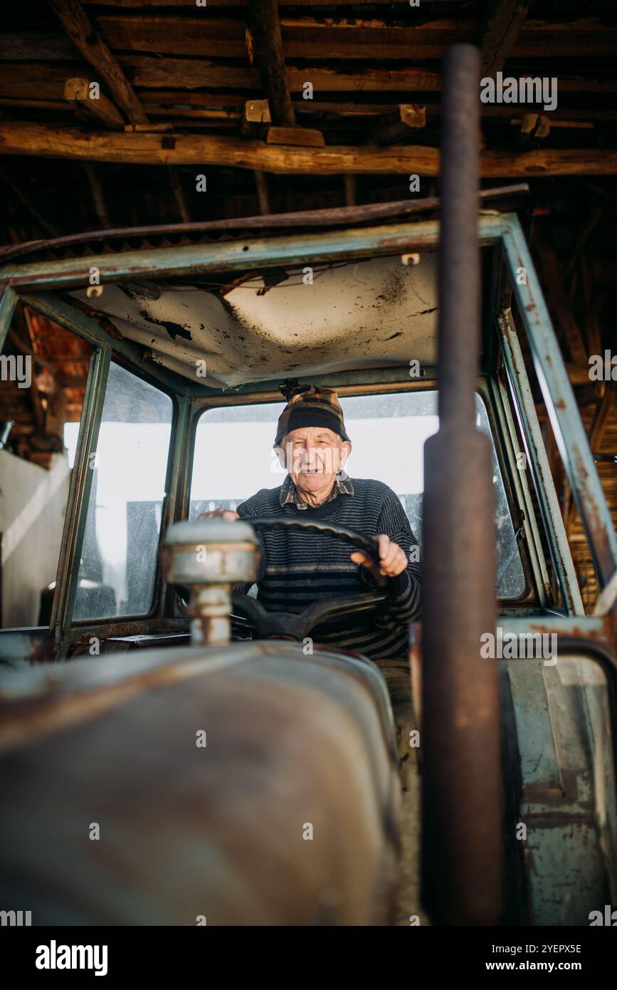 Senior man in a rusty broken tractor Stock Photo - Alamy