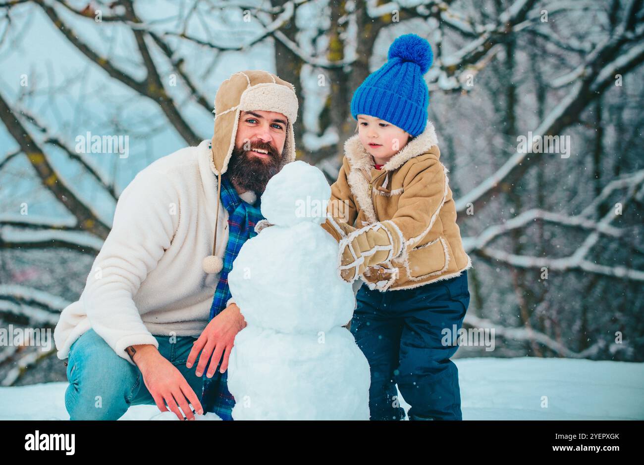 Father and son making snowman. Dad and baby son playing together ...