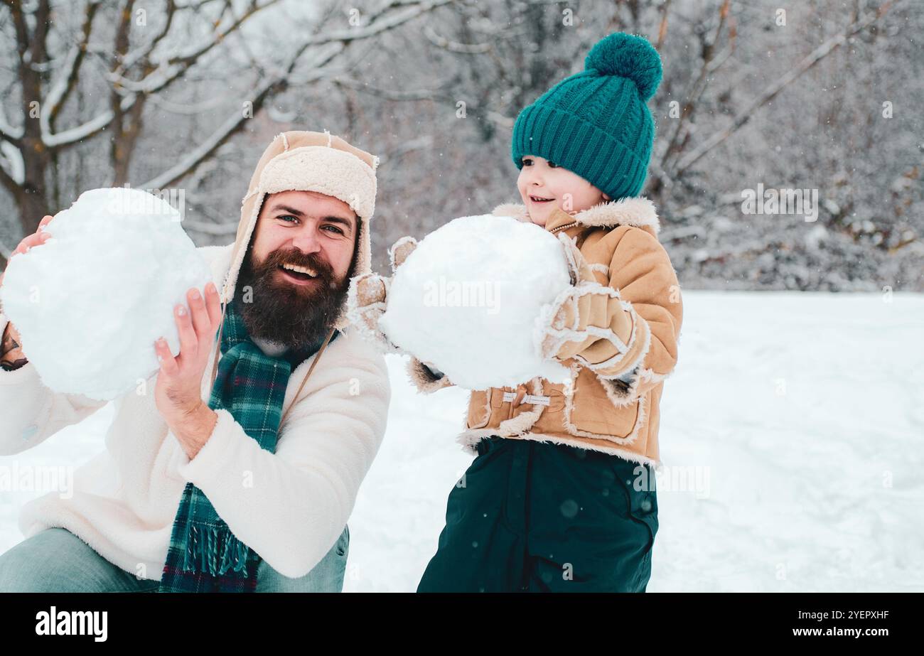 Happy father and son making snowman in the snow. Winter family in ...