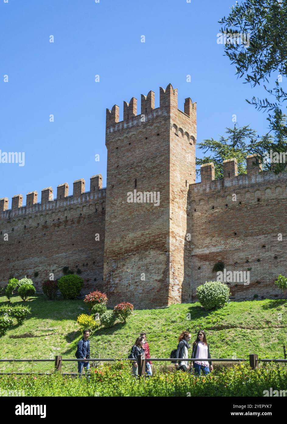 People walk in front of a tower on the defense wall of the medieval ...