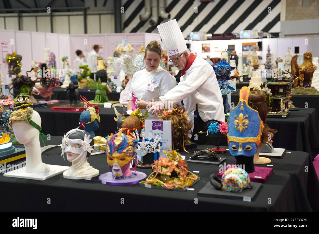 Judges examine a selection of cakes on display during the Cake ...