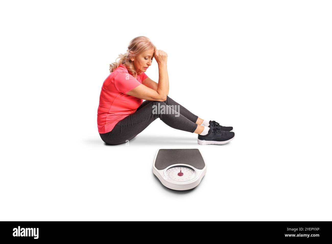 Unhappy mature woman sitting on the ground with a weight scale isolated ...