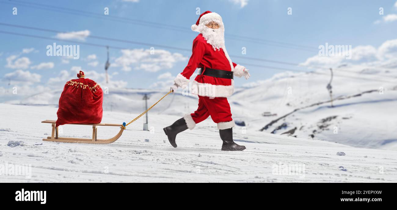Santa Claus pulling a wooden sled with sack full of presents on a snowy ...