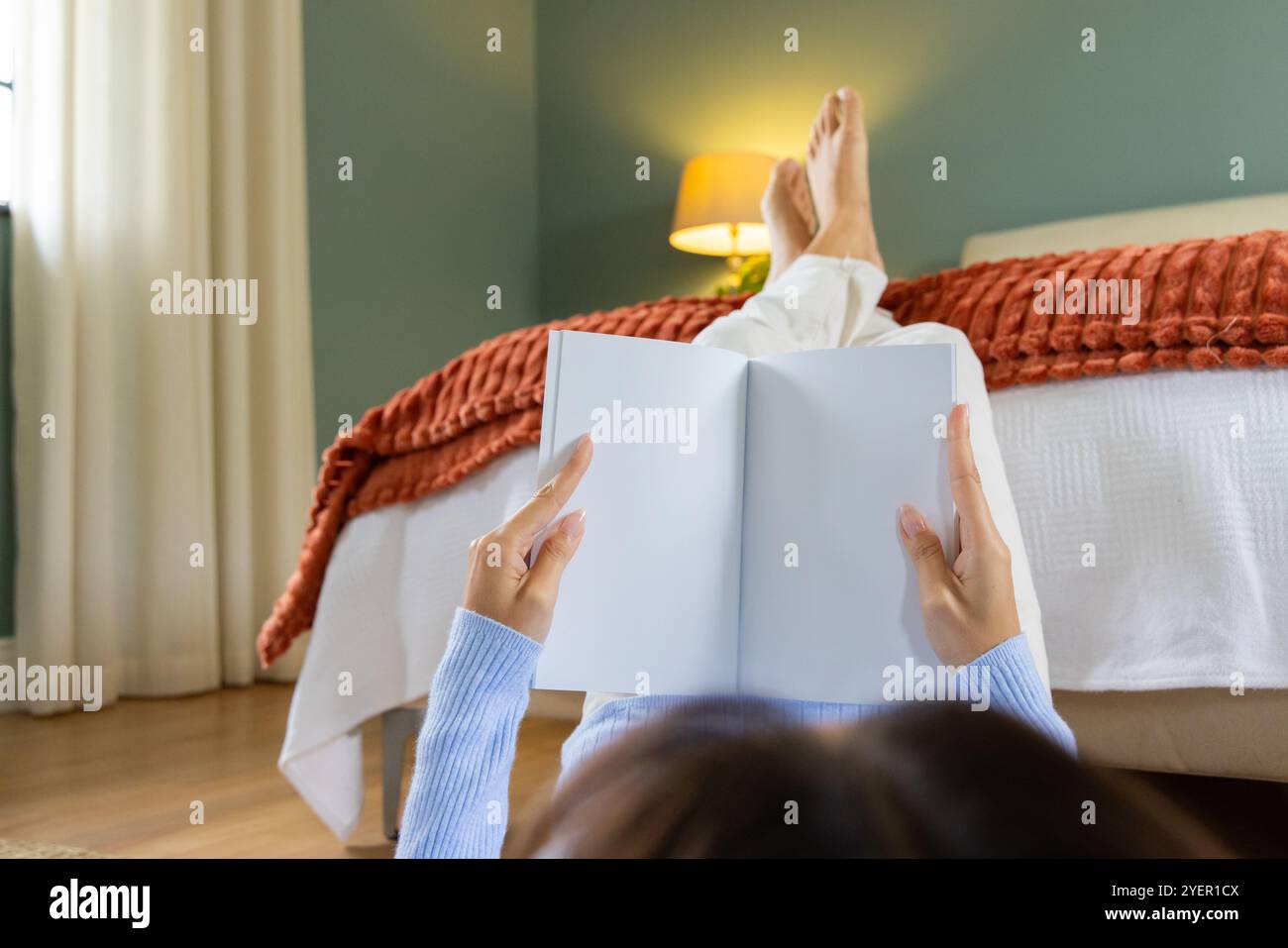 Relaxing at home, woman reading book with feet up on bed. Relaxation ...