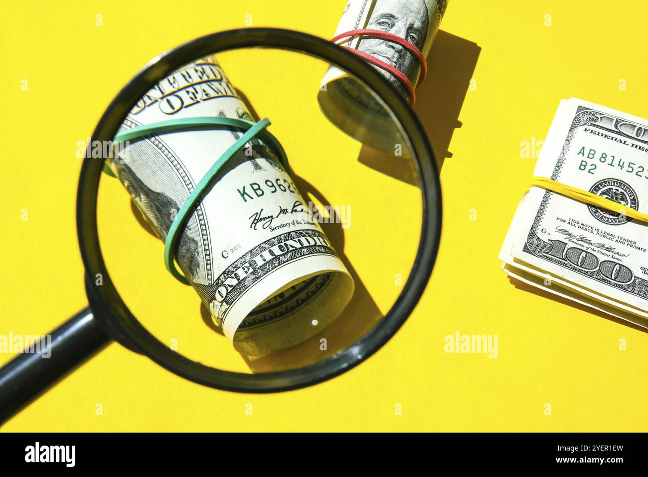 Magnifying glass on the background of a bundle of dollars close-up, one ...