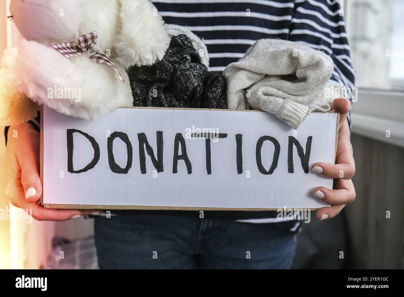 Female volunteer holding donation box with old used toys and clothes ...