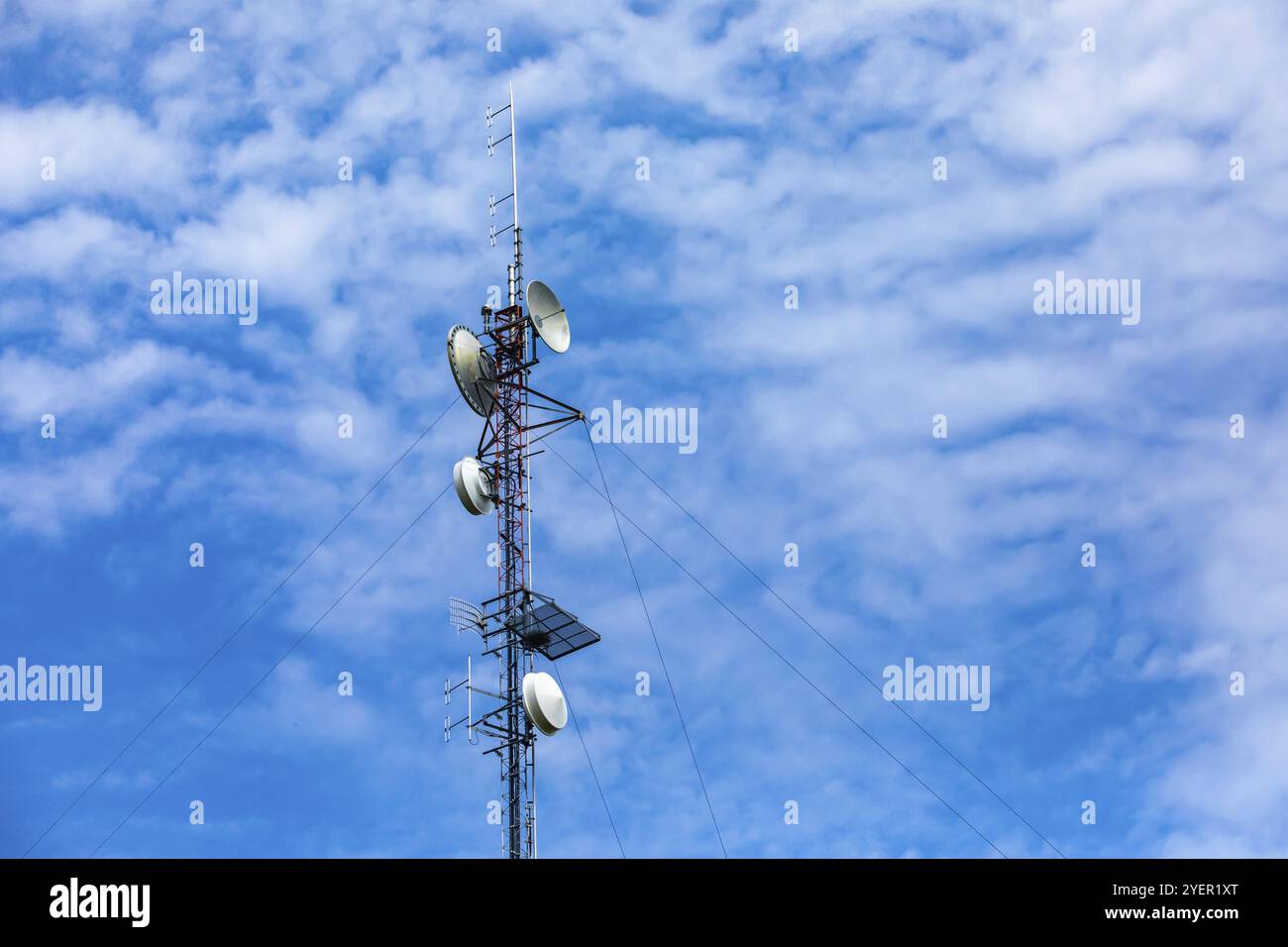 A low angle view of scattered clouds behind a cell tower ...