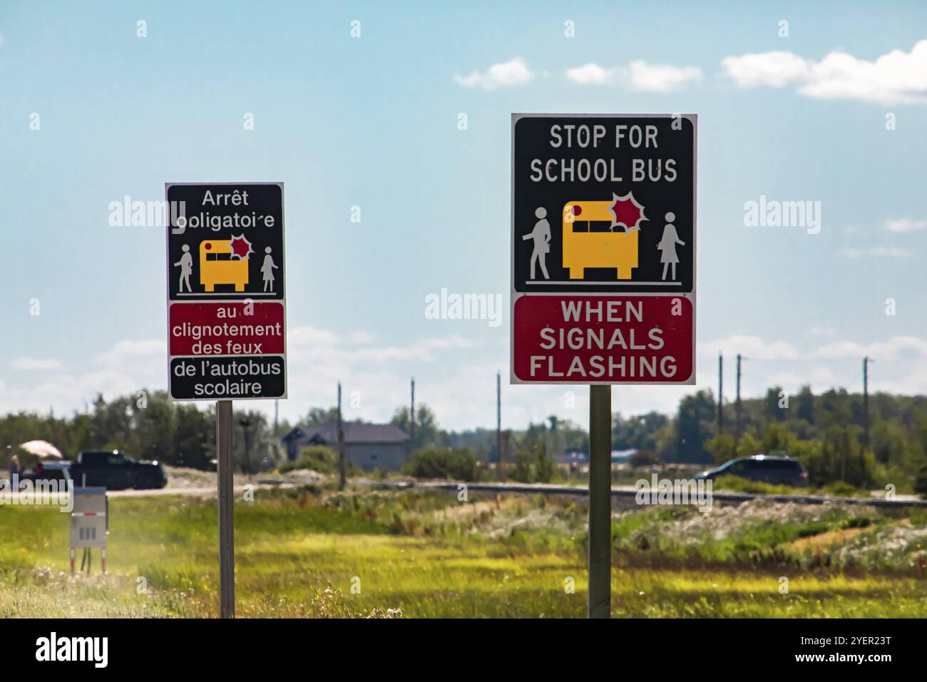 French and English two warning road signs on the roadside, stop for ...