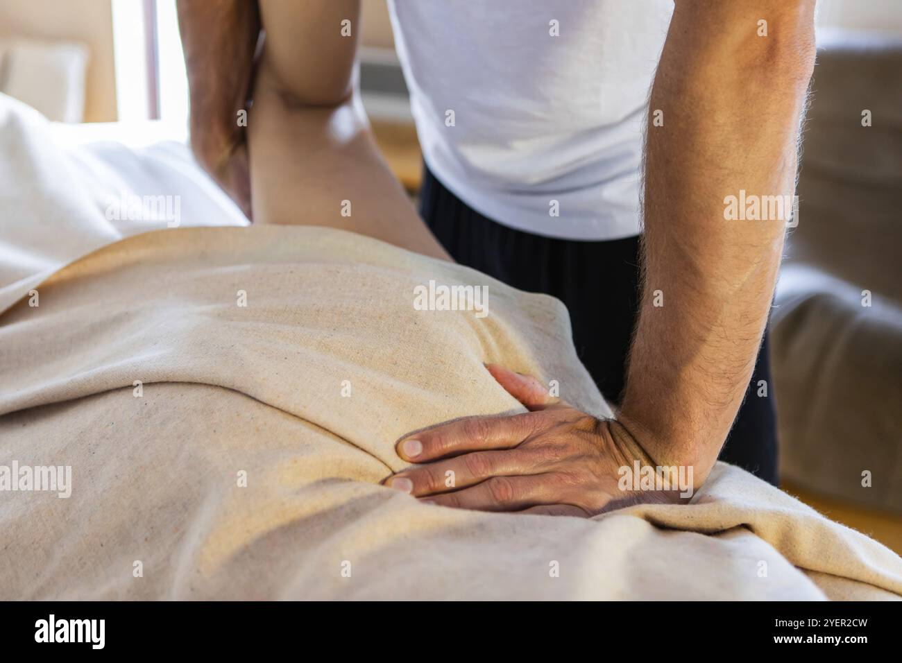 Oil leg massage therapy. Masseur massaging young female legs in a cosy ...