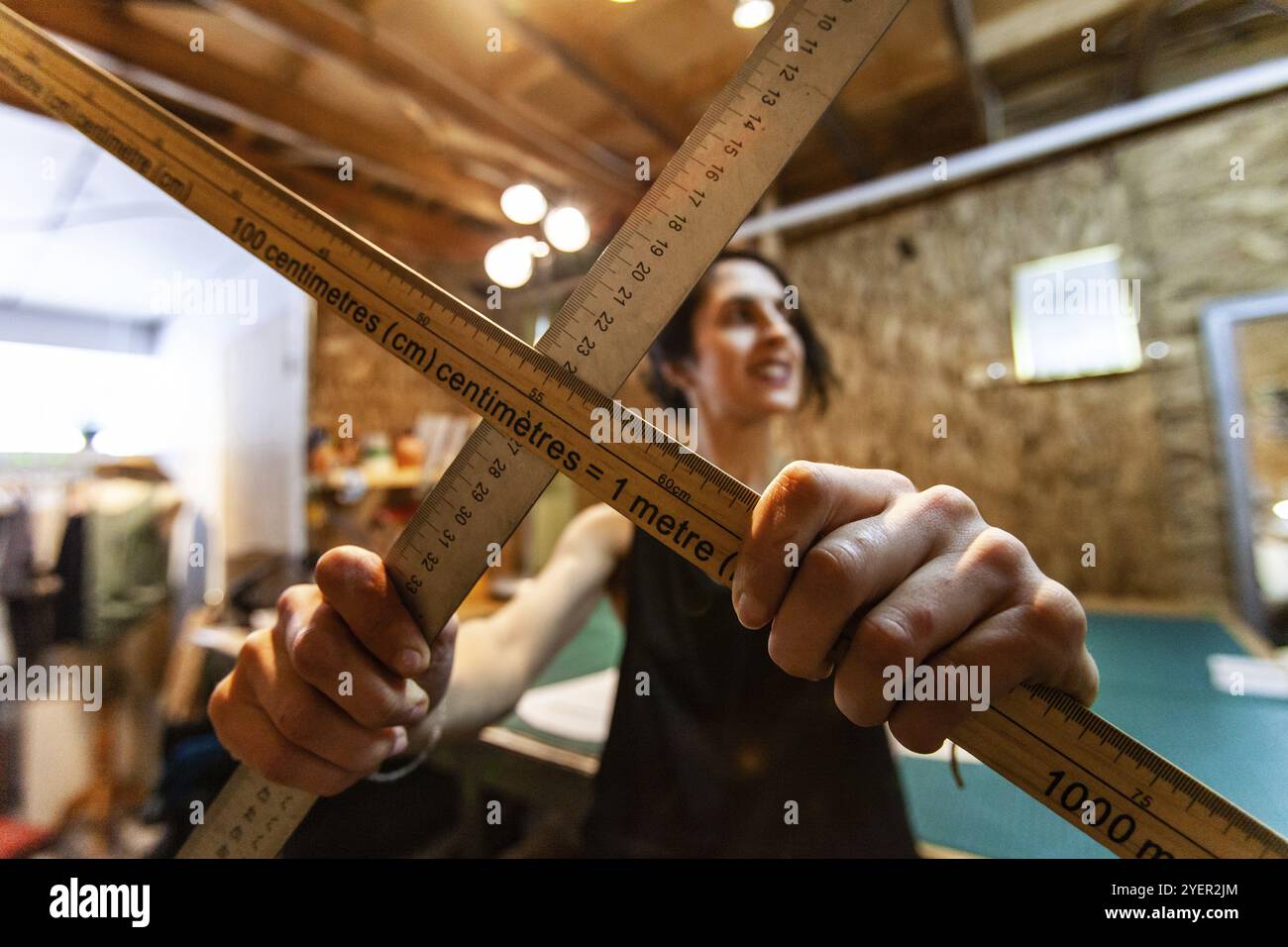 A closeup view of two wood measuring rods being held by a woman tailor ...
