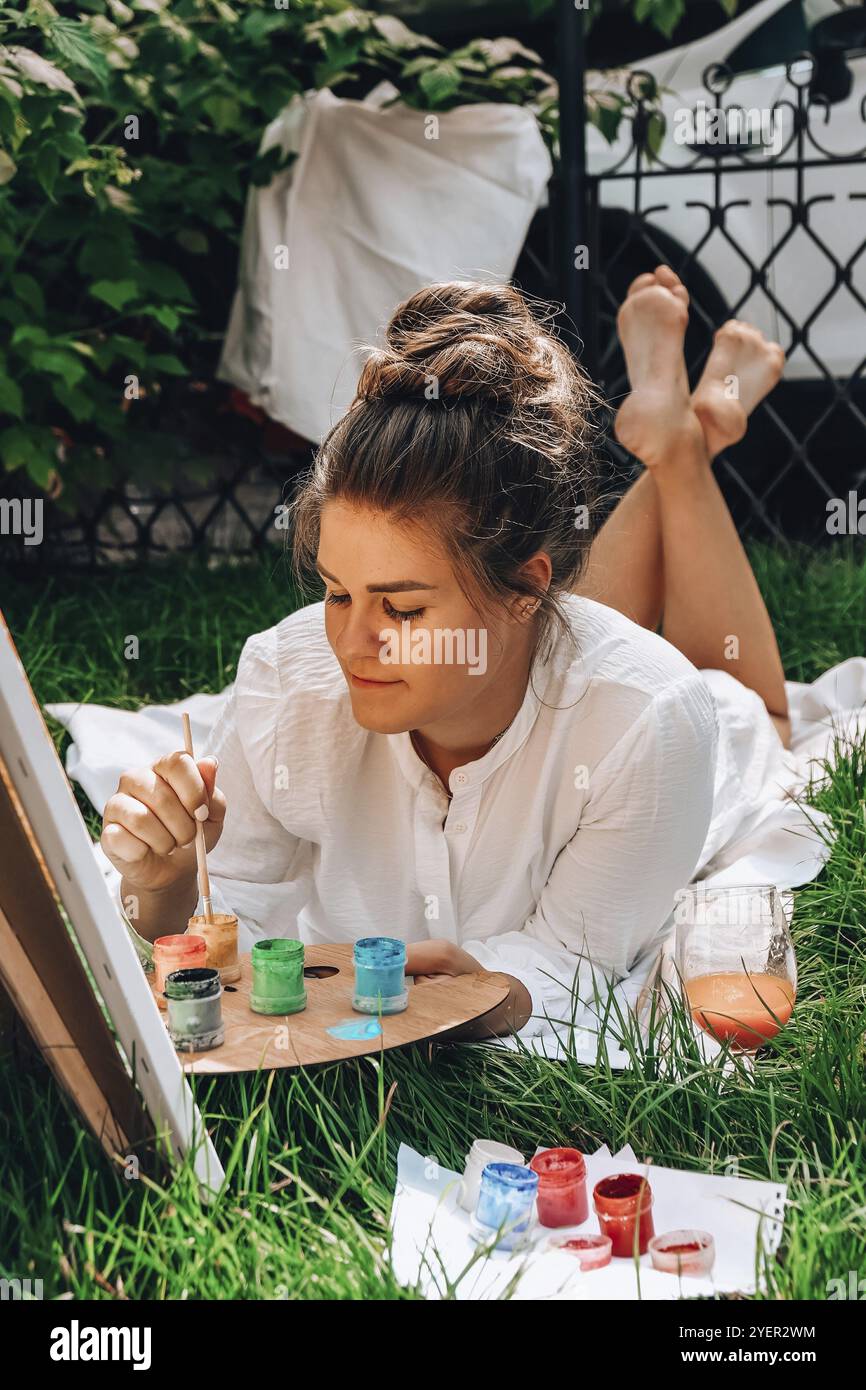 Artist painting on the easel outdoors in the garden. Open air outdoor ...