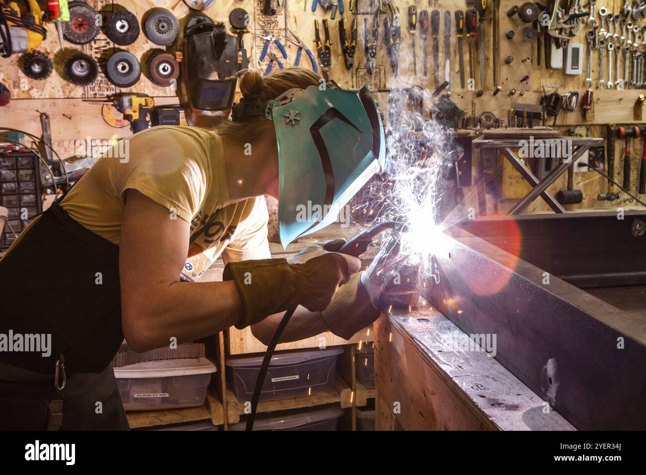A side profile view of a man operating a metal inert gas welder inside ...
