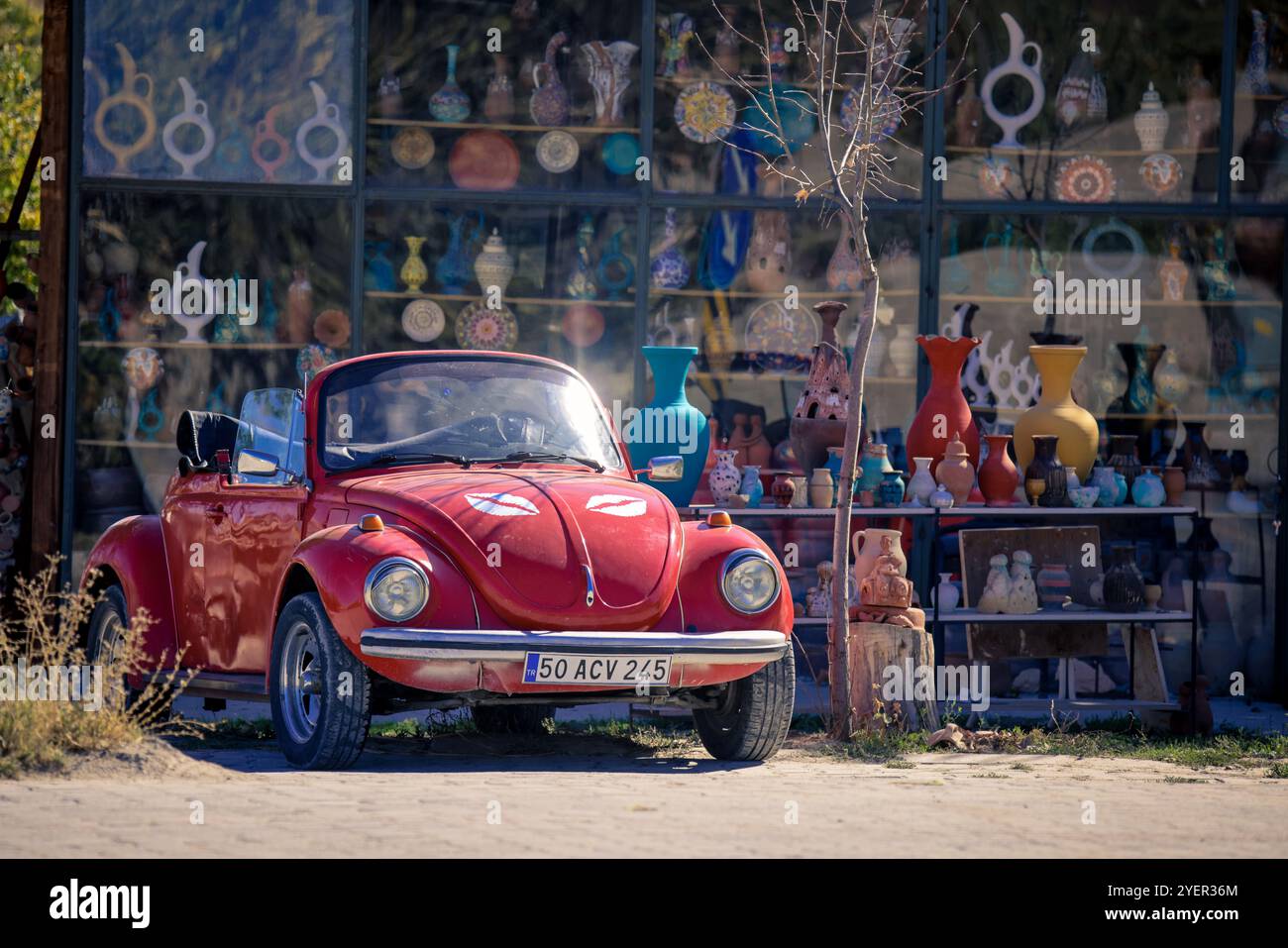 A charming red car is parked beside a shop filled with beautifully ...