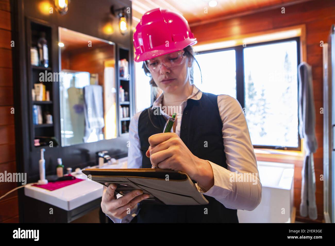 Female home inspector wearing a pink hard hat. she taking notes with ...