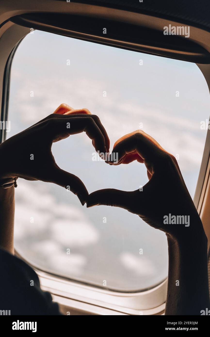 Female hand in heart shape Airplane flight. View from the window of the ...