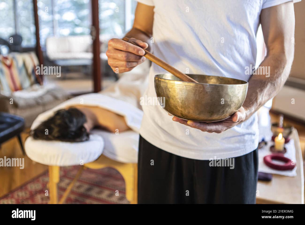 Massage therapist standing with a singing bowl in hands and giving a ...