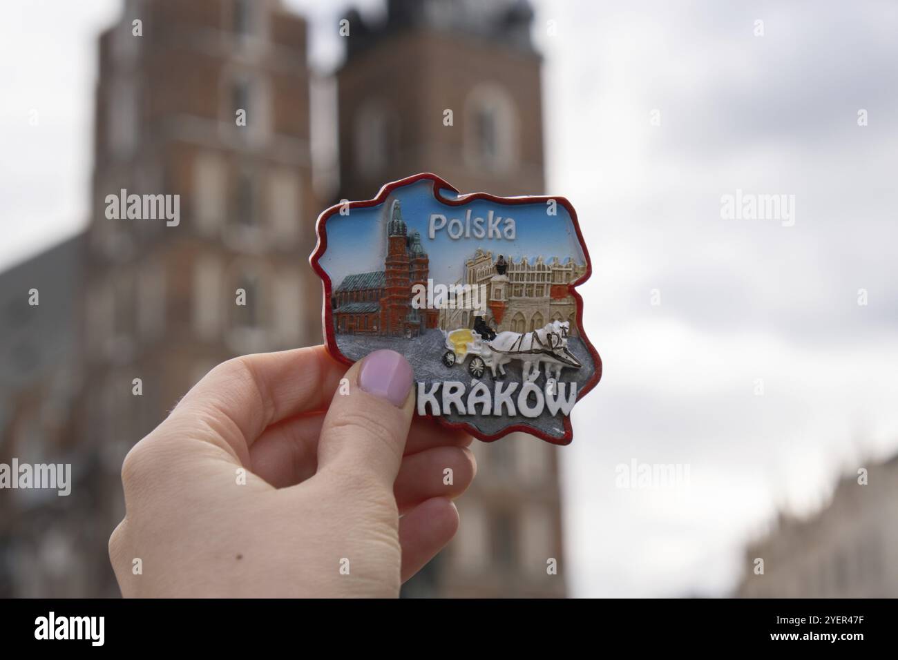 Female hand holding souvenir magnet next to St. Mary's Basilica on the ...