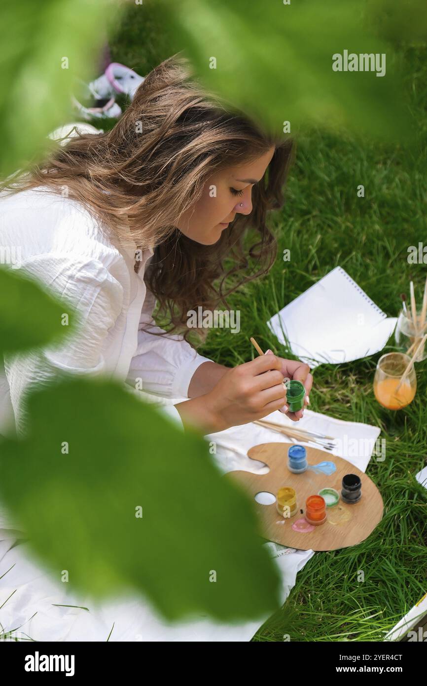 Artist painting on the easel outdoors in the garden. Open air outdoor ...