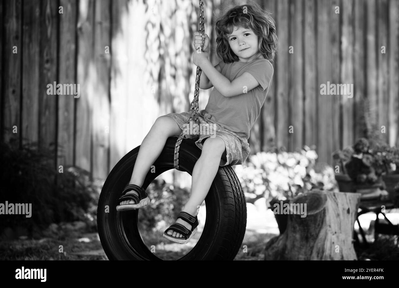 Child swing on backyard. Kid playing oudoor. Happy cute little boy ...