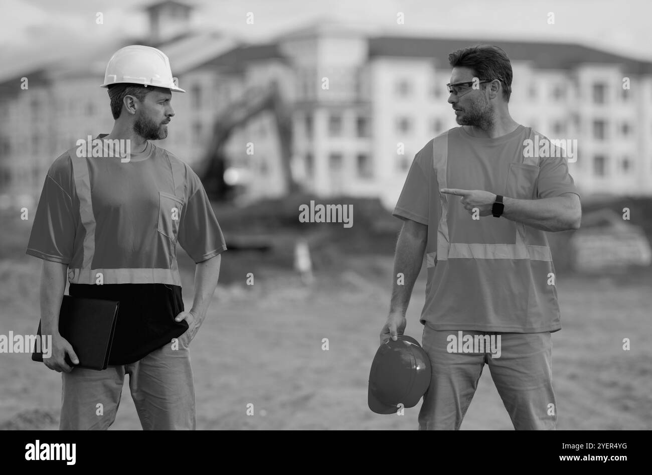 Two construction workers with hardhat helmet on construction site ...