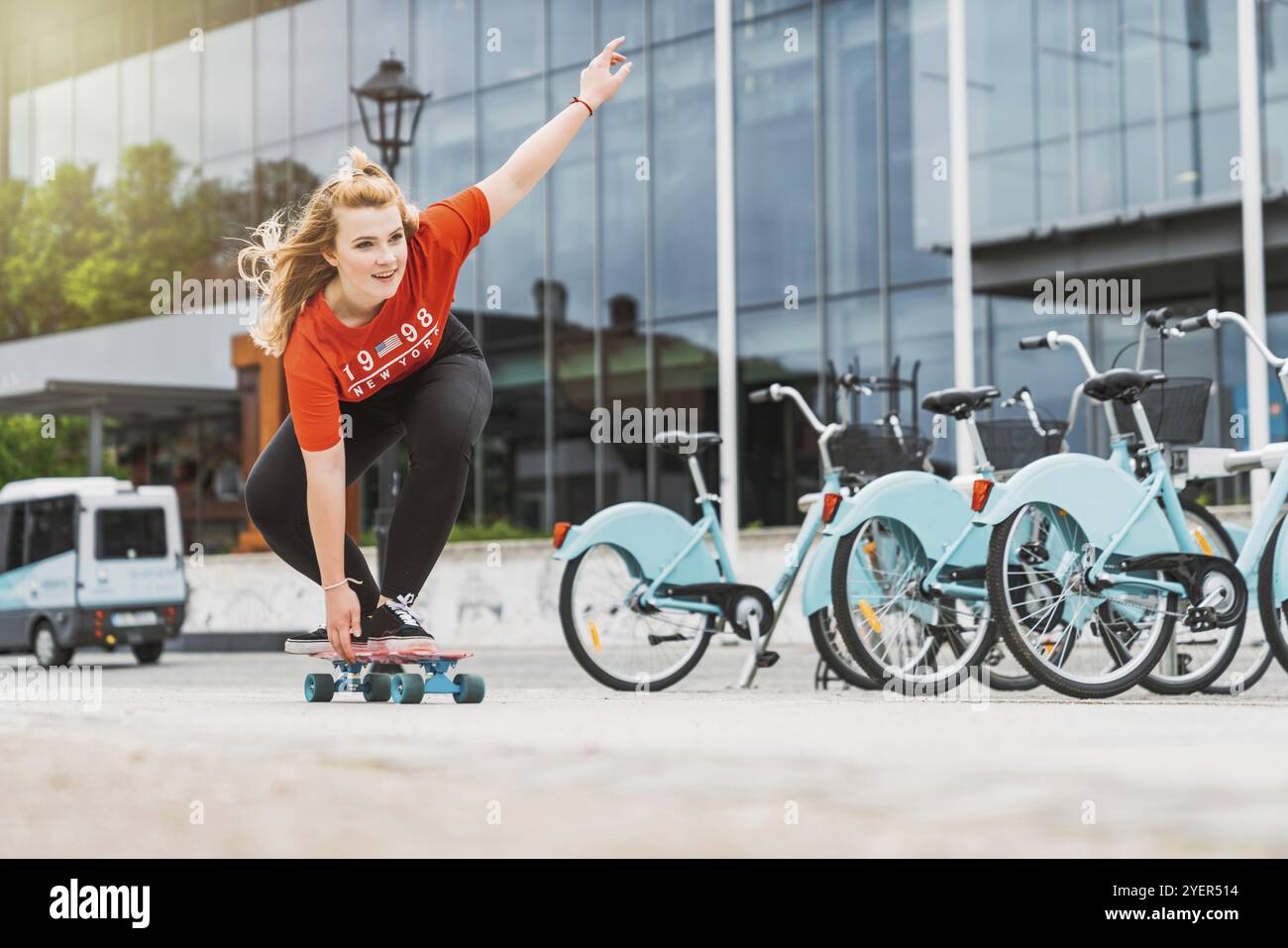 Young blonde caucasian girl having fun outside on a skateboard, wearing ...