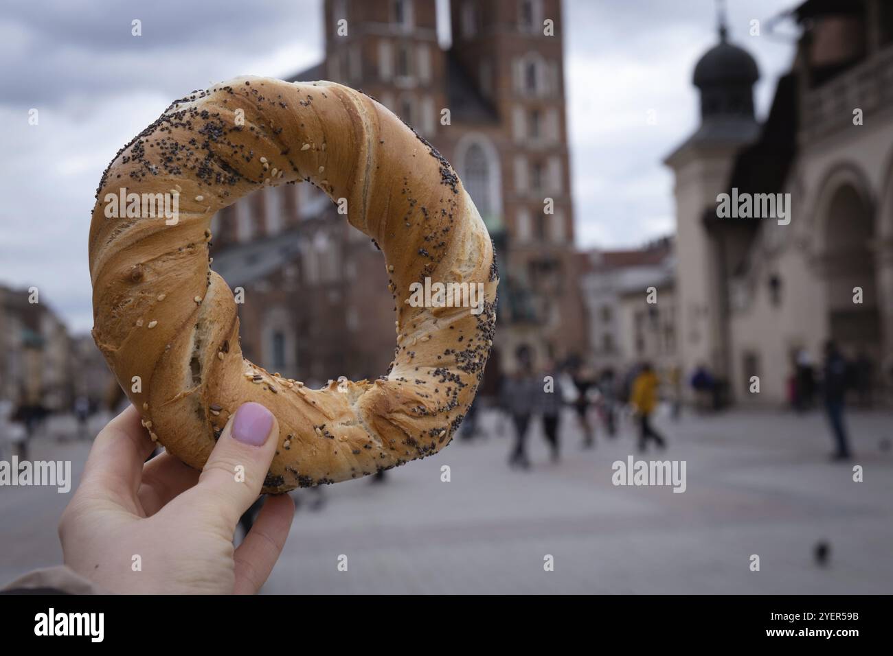 Tourist woman eating bagel obwarzanek traditional polish cuisine snack ...